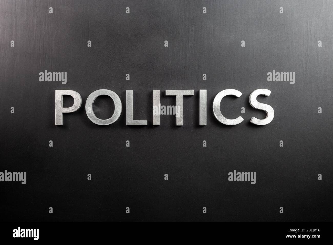 the word politics laid with aluminium letters over matte black flat ...