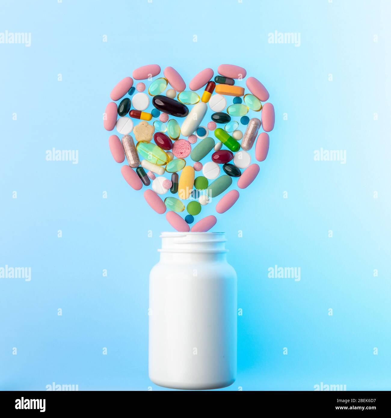 Jar of different tablets and pills in shape of heart on top of it ...