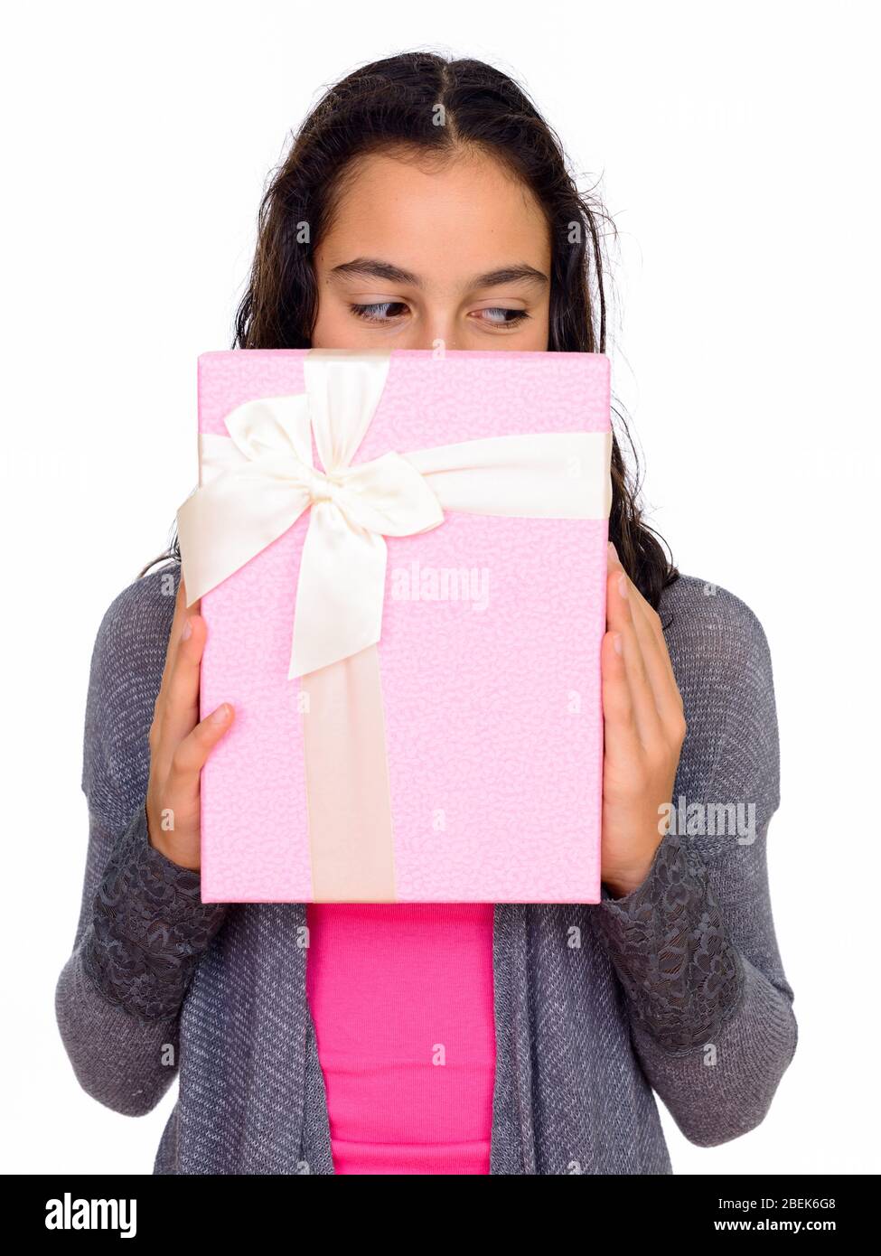 Studio shot of young beautiful teenage girl hiding behind gift box ...