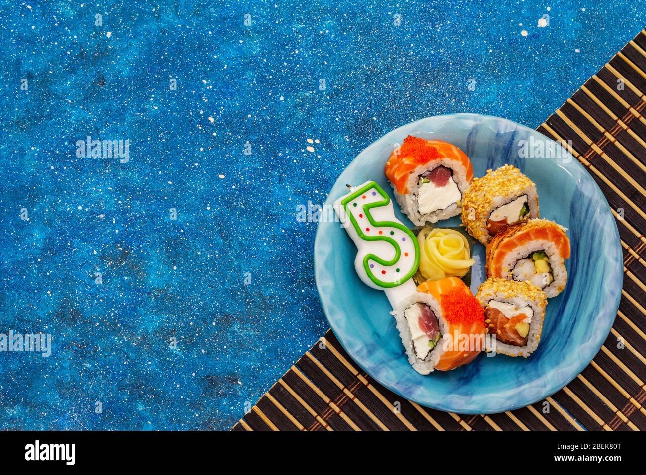 Assorted sushi with a candle in the shape of the number five. Children ...