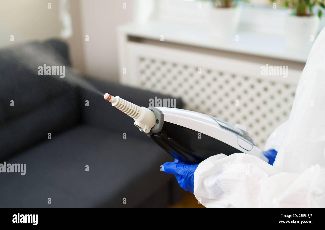 Cleaner in biohazard suit disinfecting room Stock Photo - Alamy