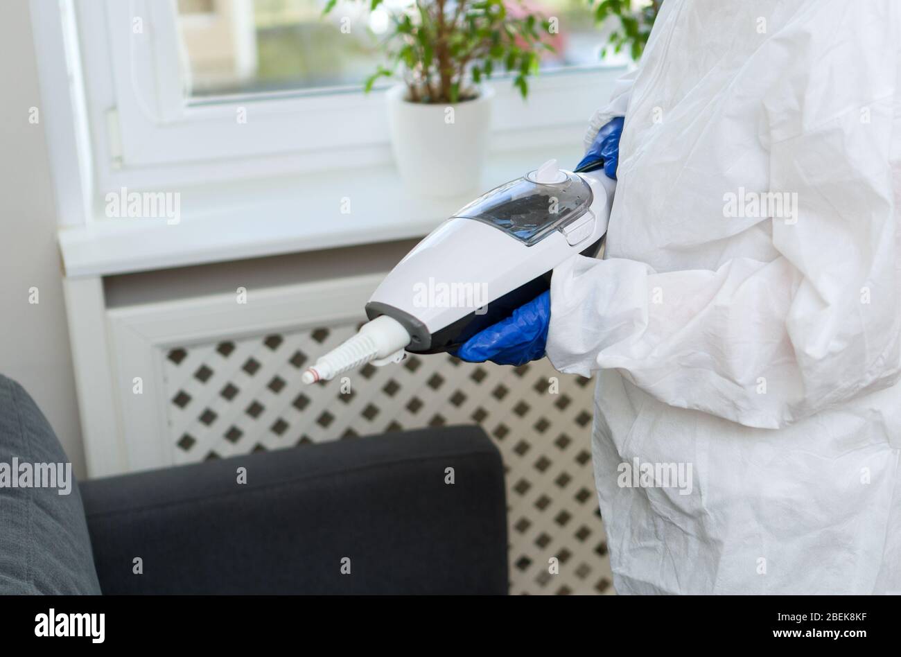 Cleaner in biohazard suit disinfecting room Stock Photo - Alamy
