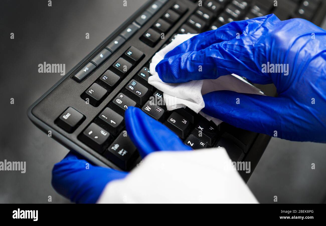 Hand in protective glove with napkin cleaning keyboard. Covid-19 ...
