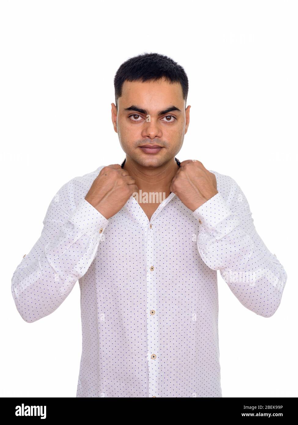 Studio shot of young handsome Indian man adjusting collar isolated ...