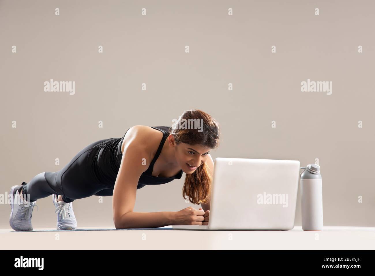 Woman planking while looking at the laptop in front of her Stock Photo ...