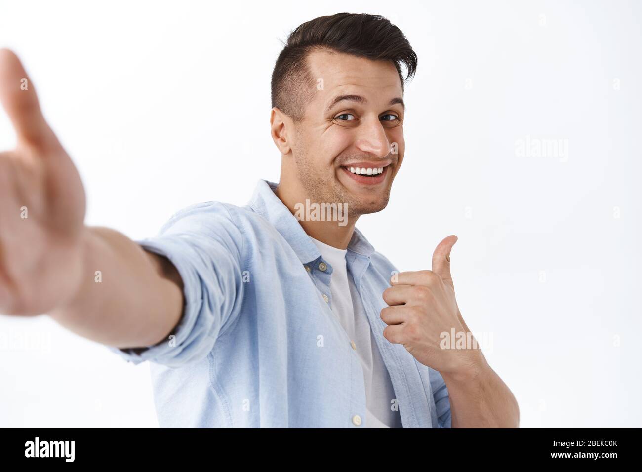 Portrait of handsome friendly guy show thumb-up as taking selfie in ...