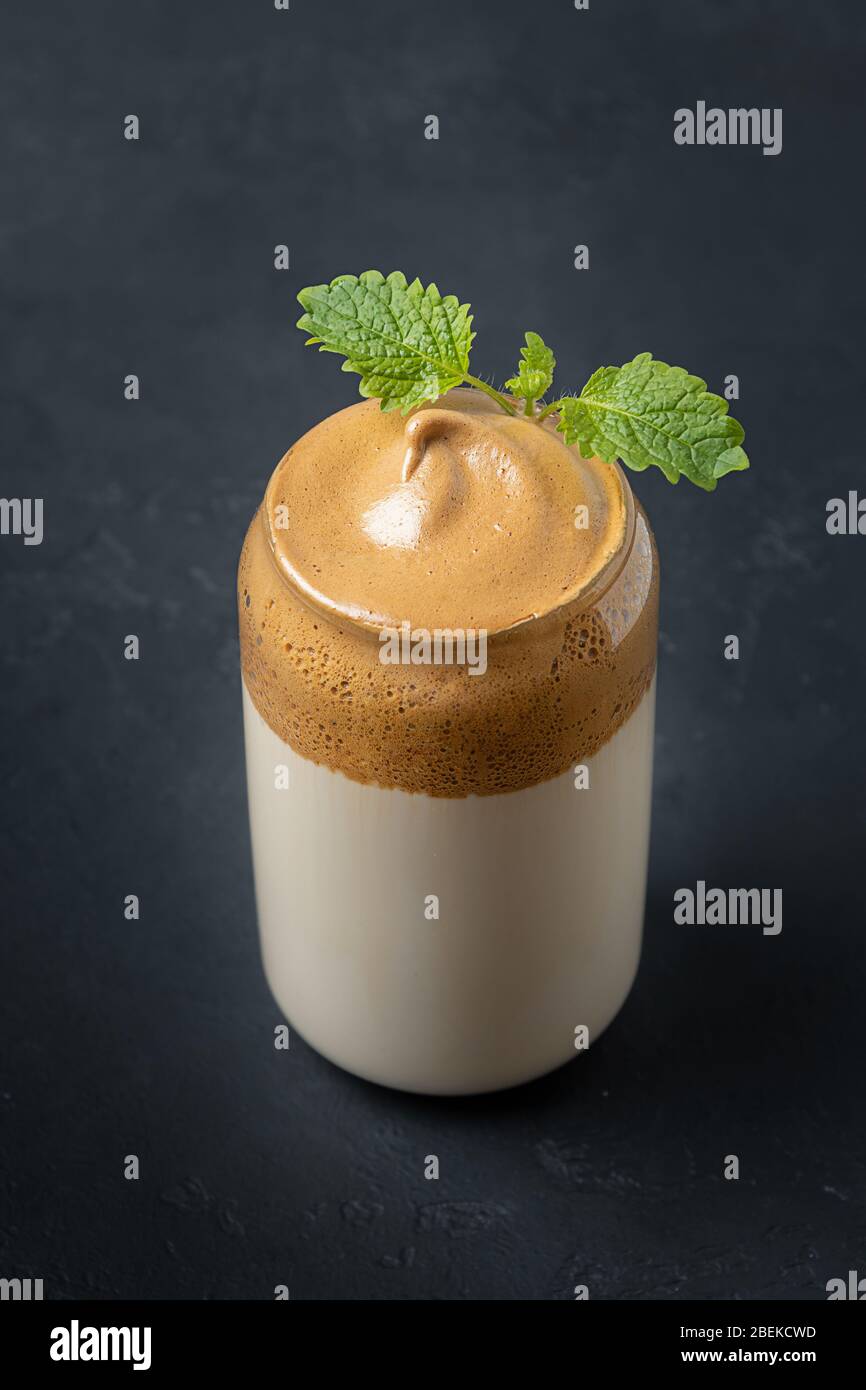 Dalgona frothy coffee in glass garnish melissa on black. Trend korean ...