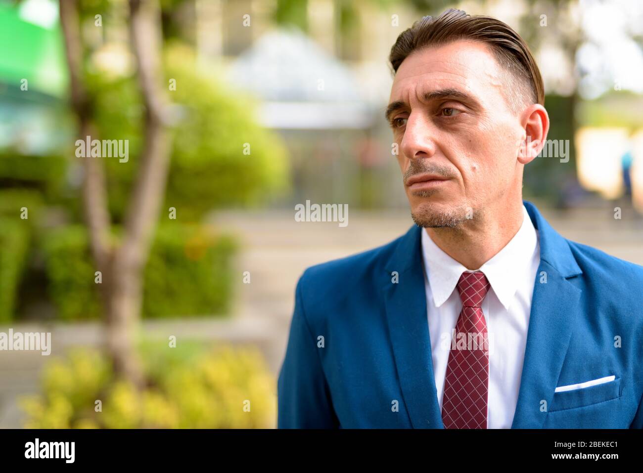 Mature handsome Italian businessman relaxing outside of the building ...