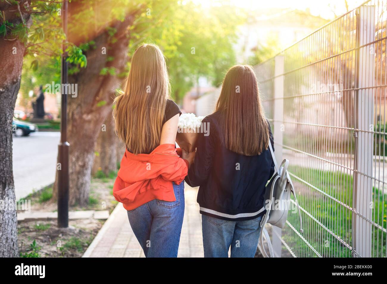 Two happy girls with backpacks walking around the city Stock Photo - Alamy