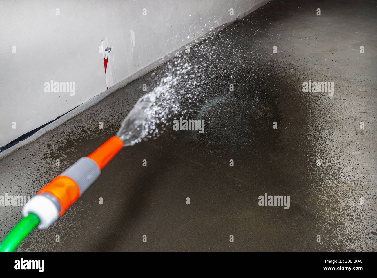 Watering with a garden hose a newly poured floor screed at home to ...