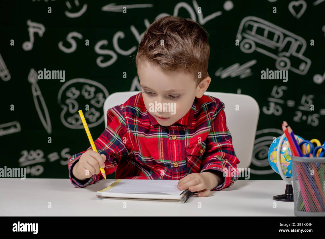 Cute child boy doing homework. Clever kid drawing at desk. Schoolboy ...