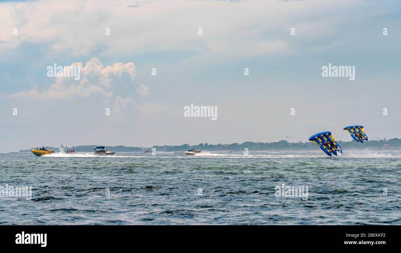 Horizontal panoramic of two flying fish rides taking off in Bali ...