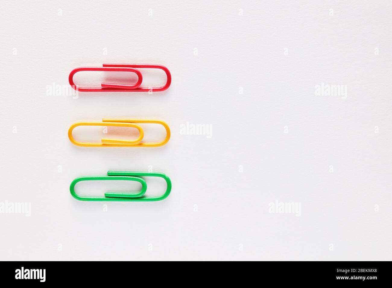 Three colorful paper clips in a row on white background with copy space ...