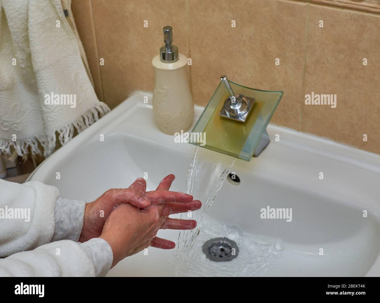 Washing hands over a sink while water is flowing from a faucet Stock ...