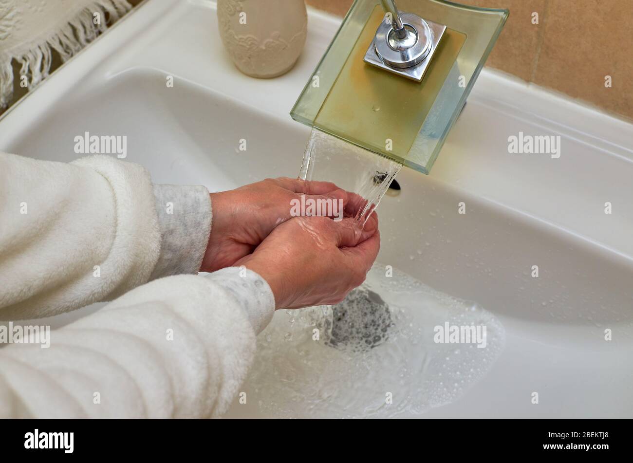 Washing hands over a sink while water is flowing from a faucet Stock ...