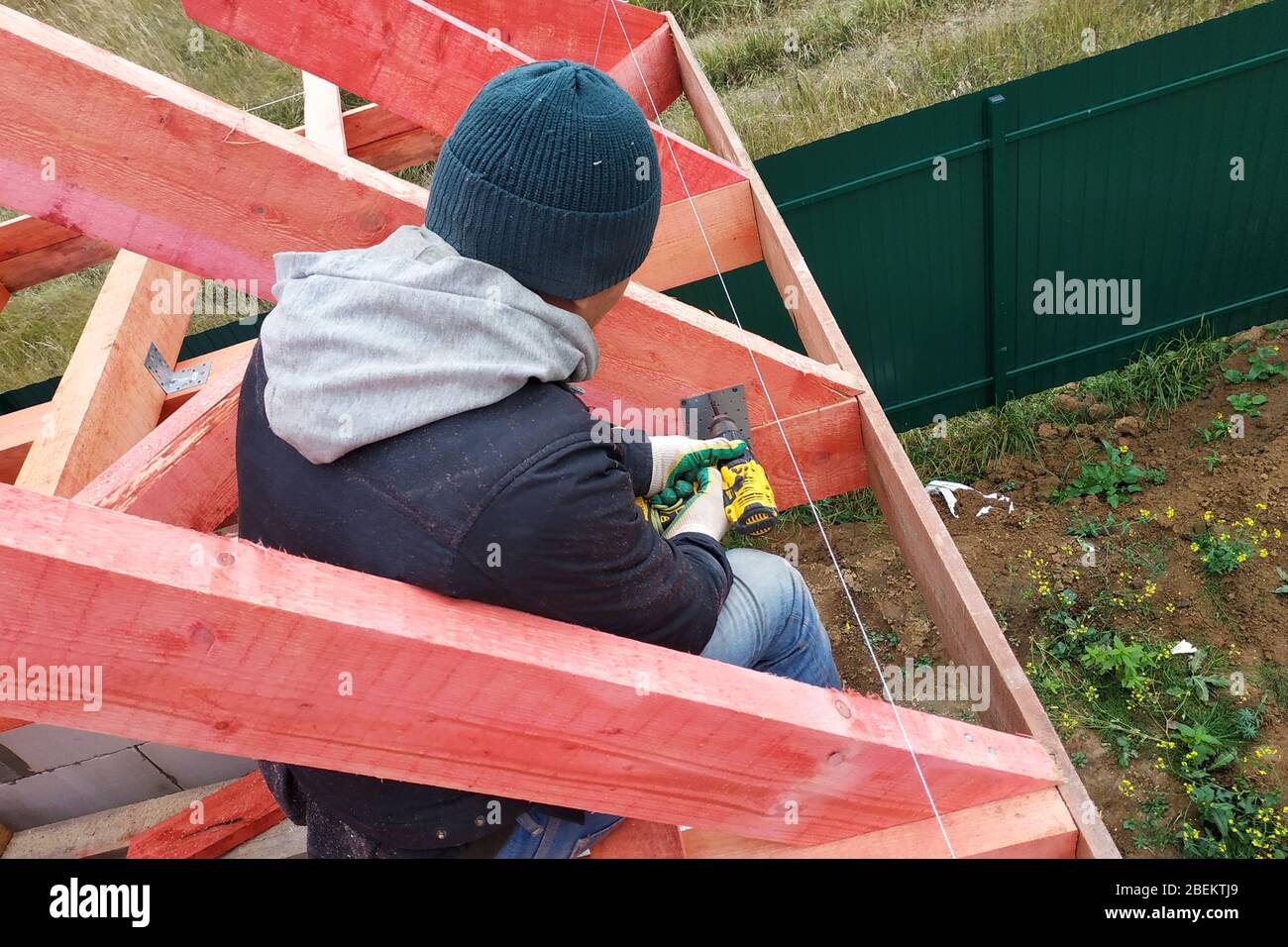 A man fastens two wooden beams with a self-tapping screw, installing ...