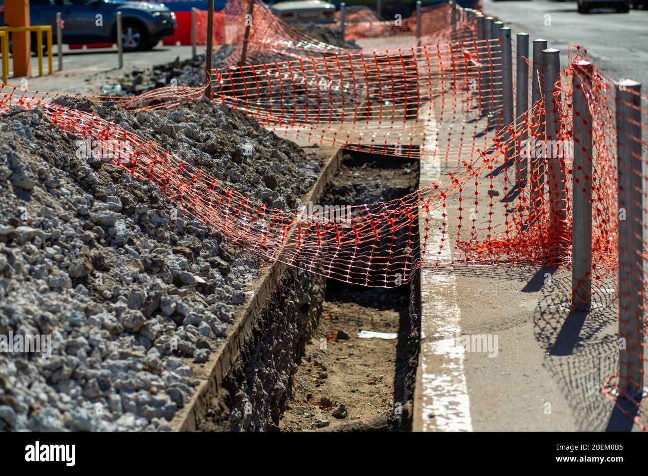 Repair work on the city street. A freshly dug trench is fenced with a ...
