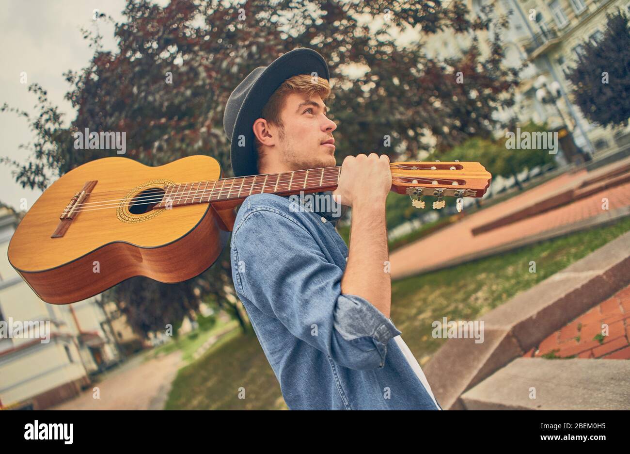 Young musician walkin with acoustic guitar at street Stock Photo - Alamy