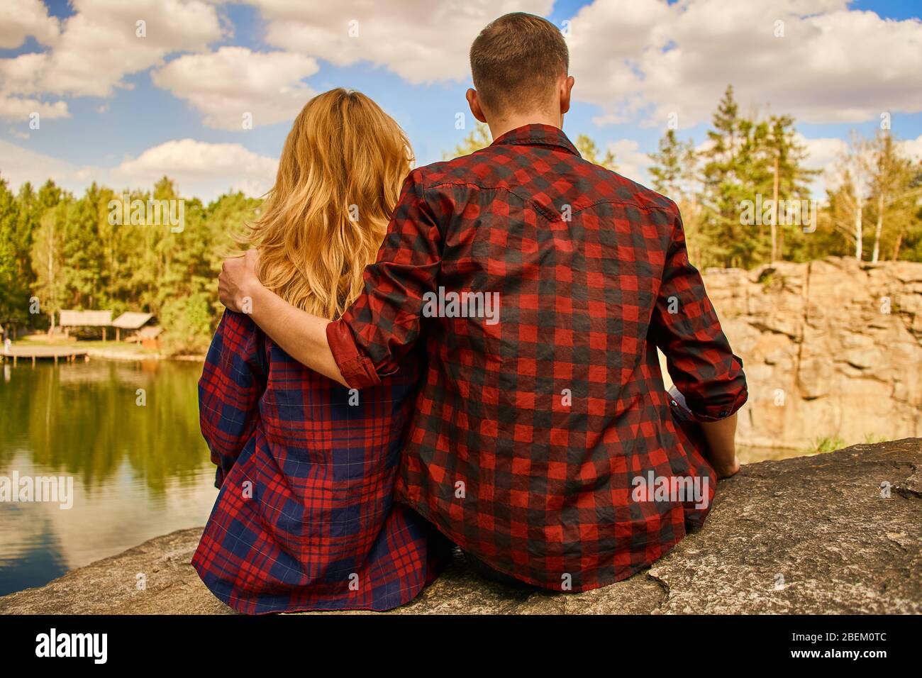 Cute couple sits at rock near the lake at forest and canyon background ...