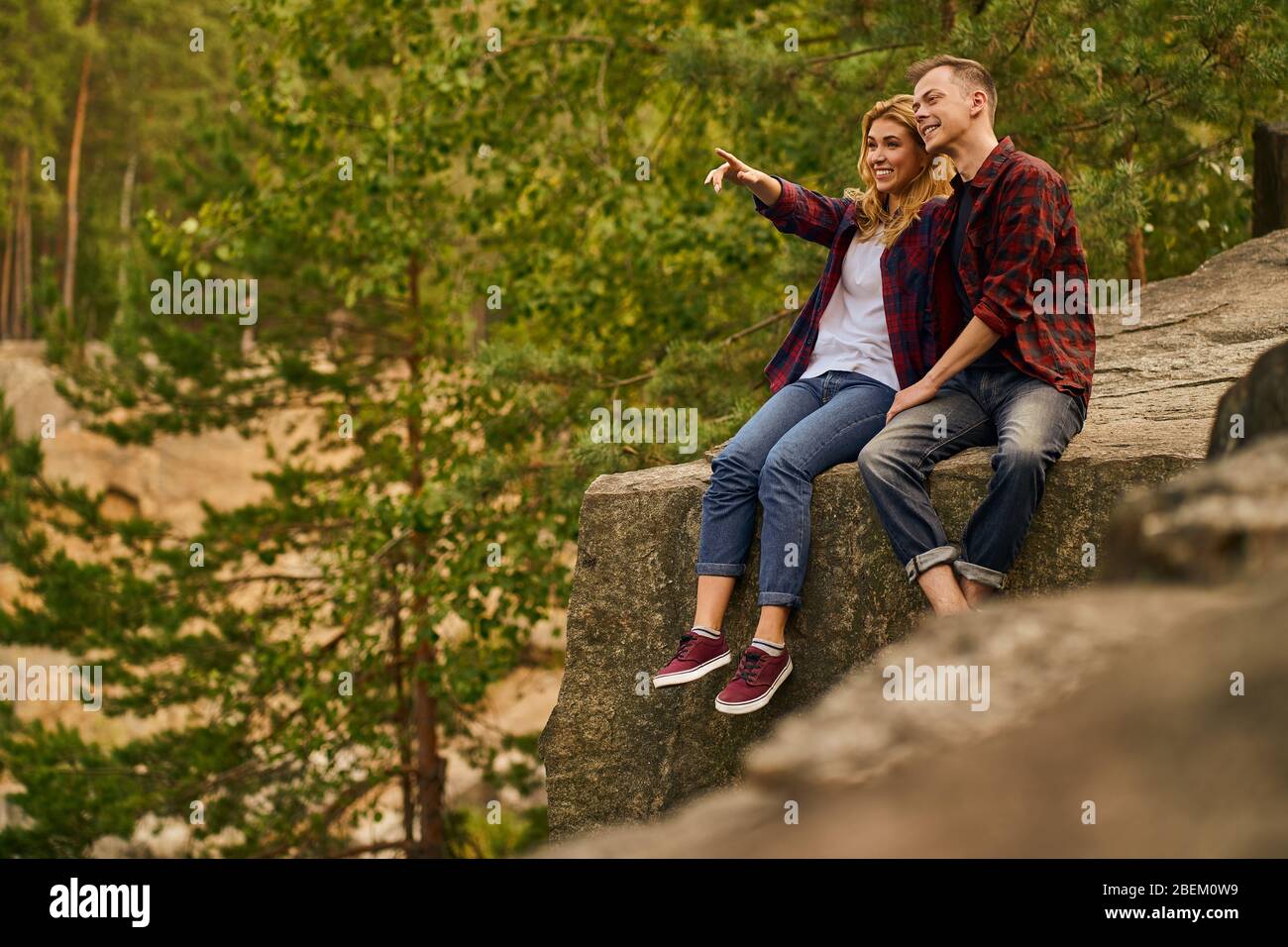Cute couple sits on the rock at forest and canyon background. Travel ...
