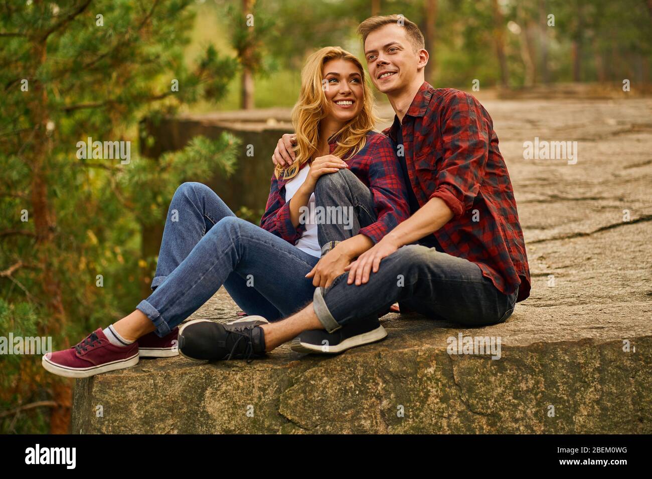 Cute couple sits on the rock at forest and canyon background. Travel ...