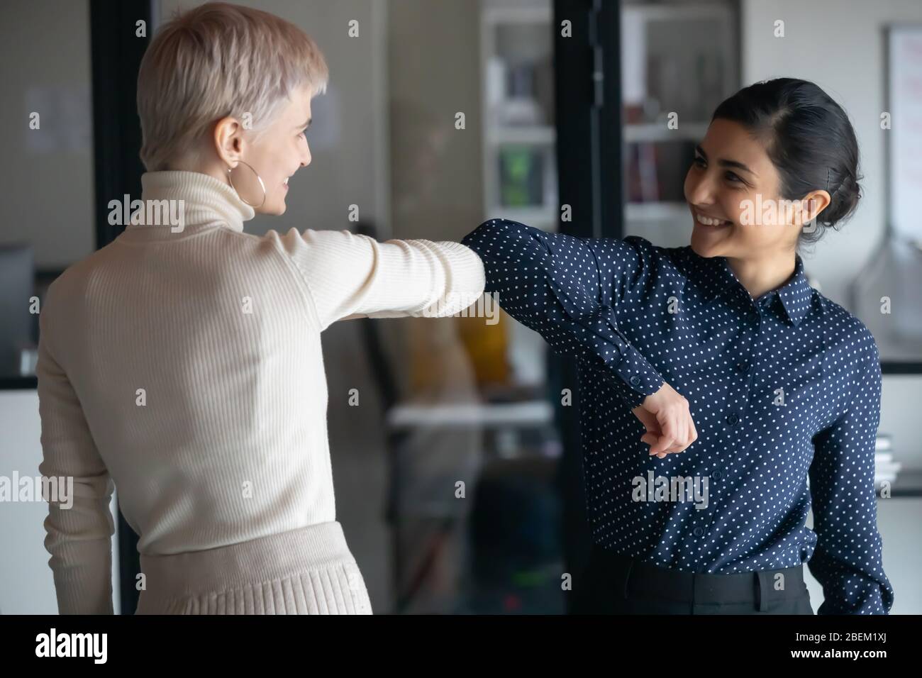 Smiling female colleagues greeting during coronavirus pandemic Stock ...