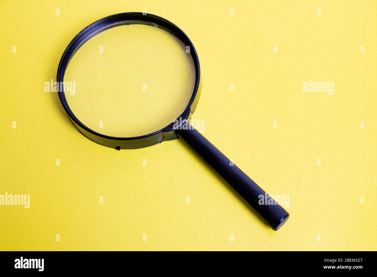 Big magnifier on a yellow background closeup Stock Photo - Alamy