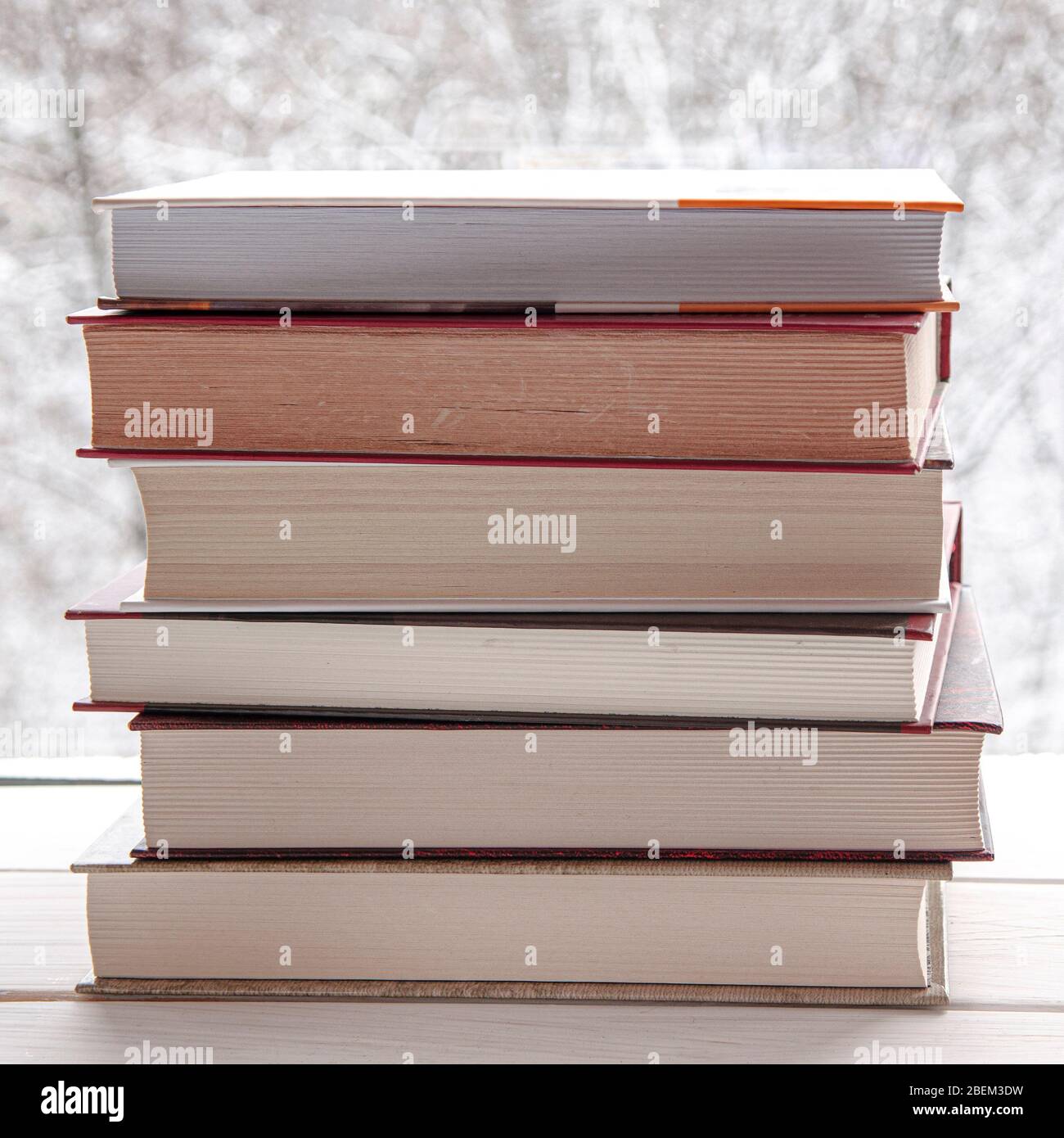 Book stack on wood desk and blurred bookshelf in the library room ...