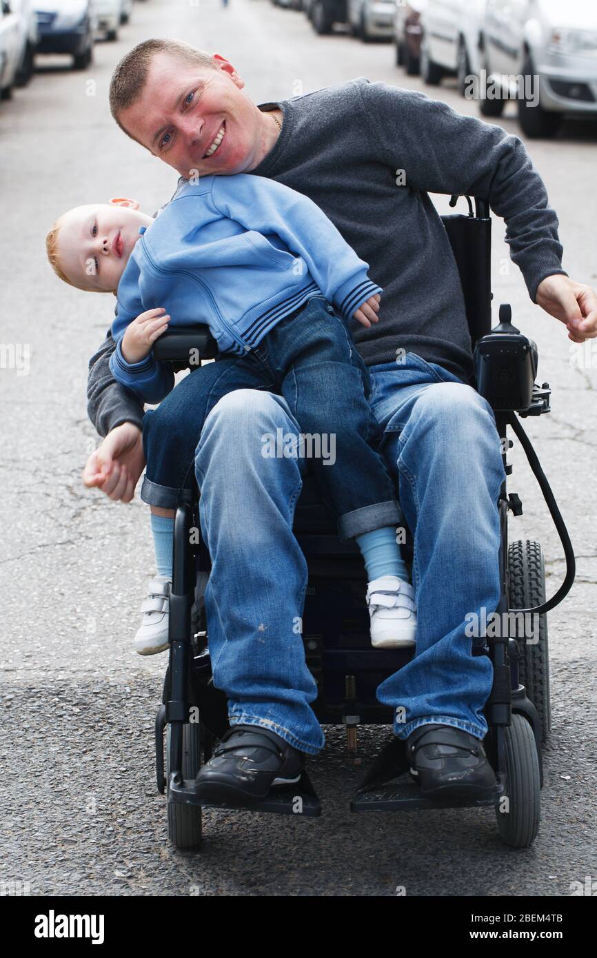 Disabled man with little son on wheelchair Stock Photo - Alamy