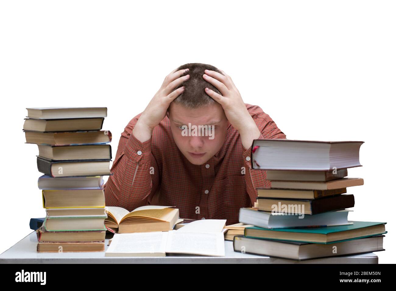 Confused guy sitting at a table with a big pile of books isolated on a ...