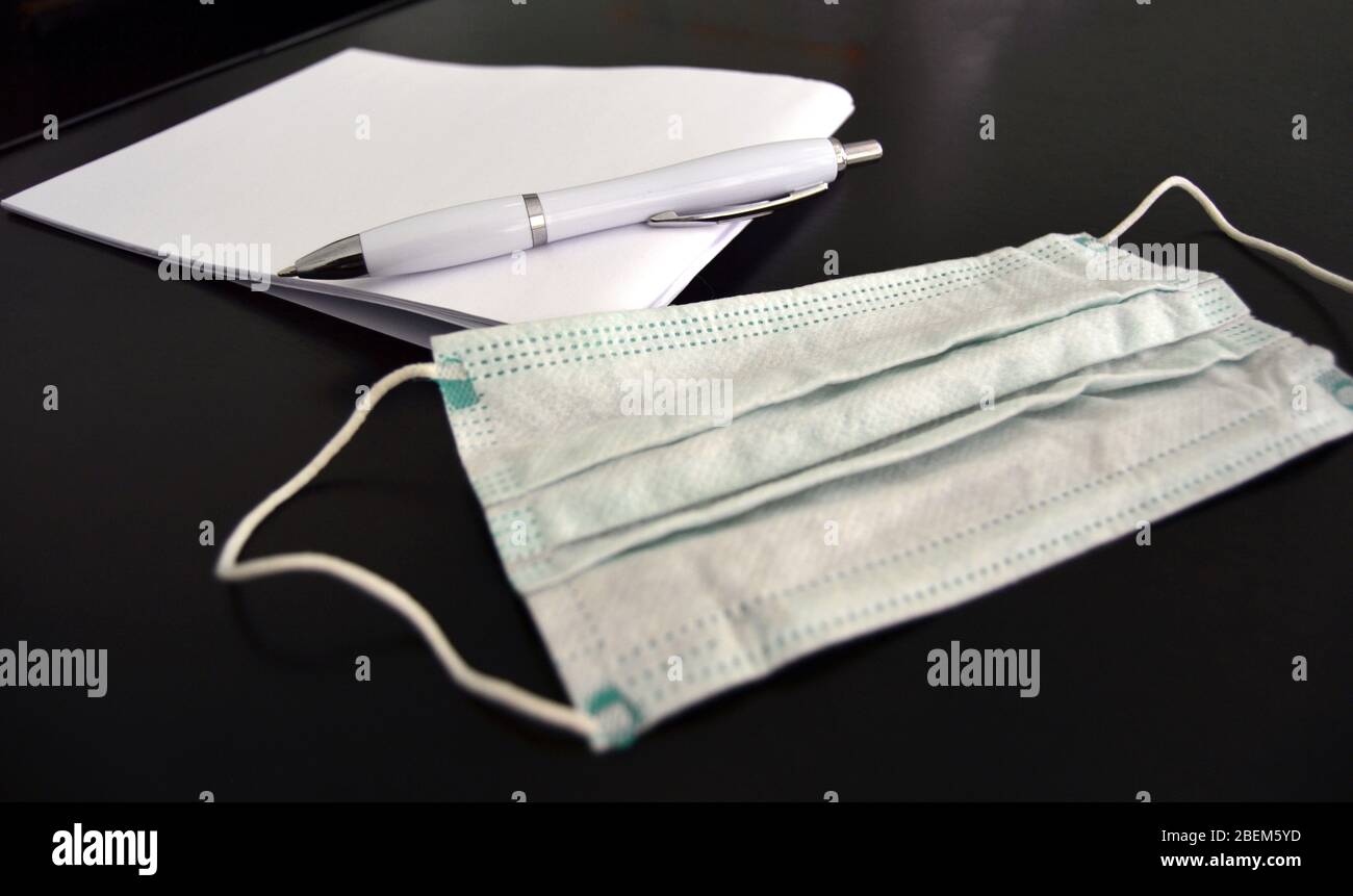 Containment surgical face mask next to paper notepad and pen on a desck ...