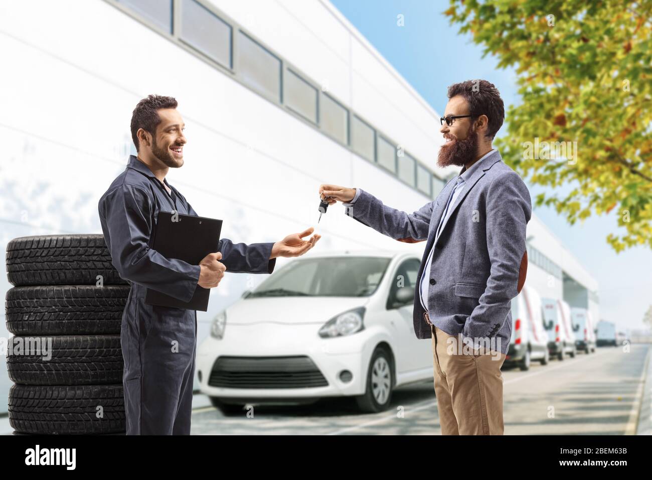 Customer giving a car key to an auto mechanic in front of a car service ...
