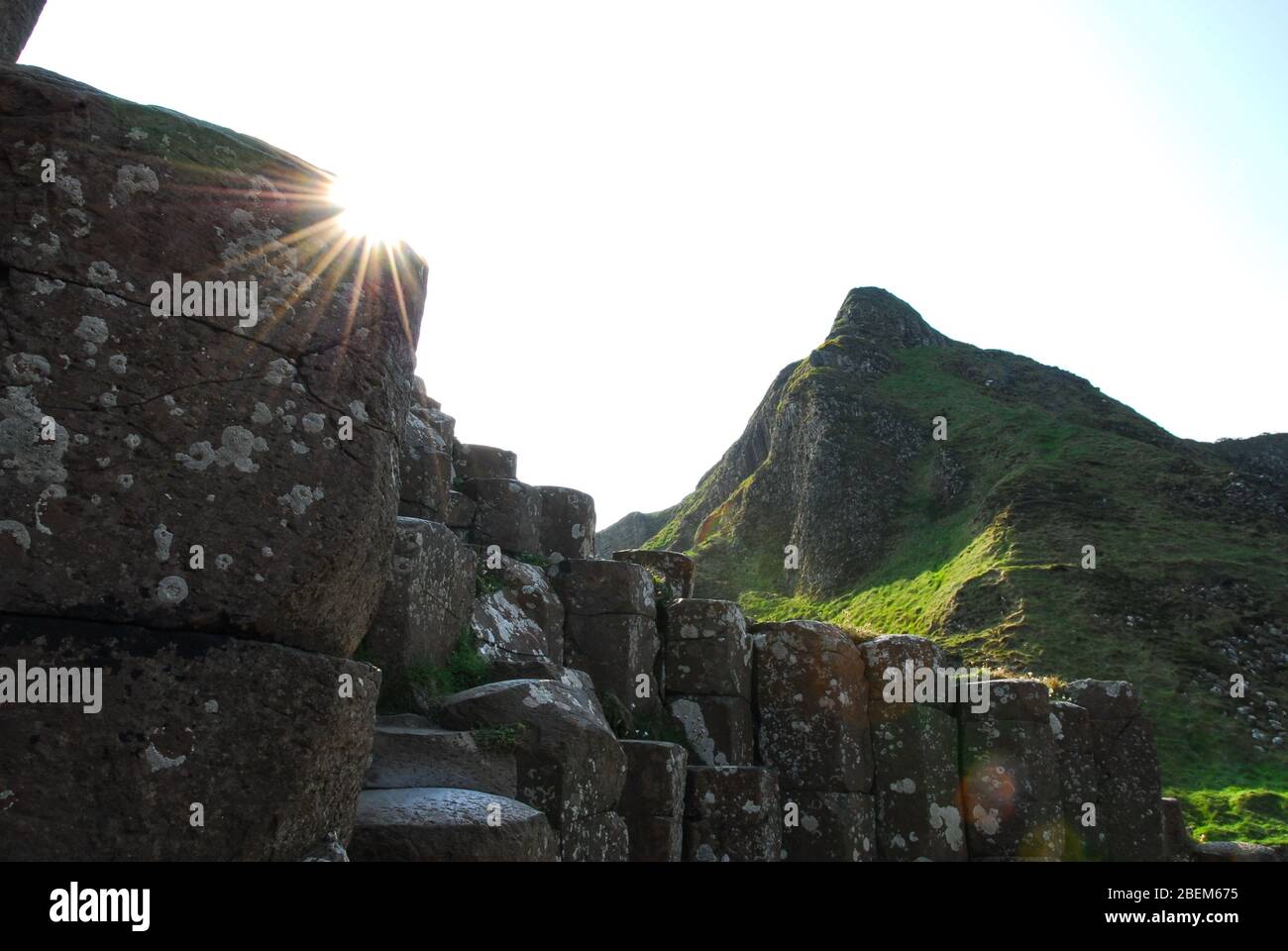 The sun bursting over some stones at the Giant's Causeway, Antrim Coast ...