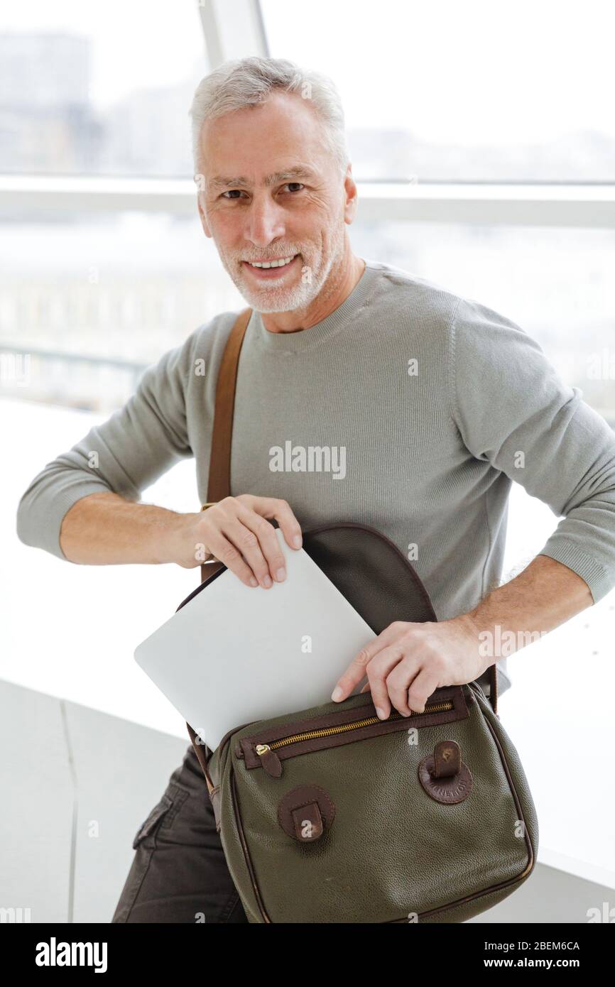 Picture of a pleased senior grey-haired bearded businessman indoors put ...