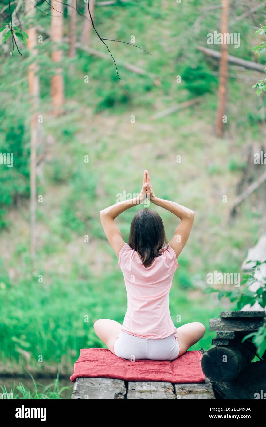 Woman practicing yoga in the woods, in nature, sitting back. Health ...