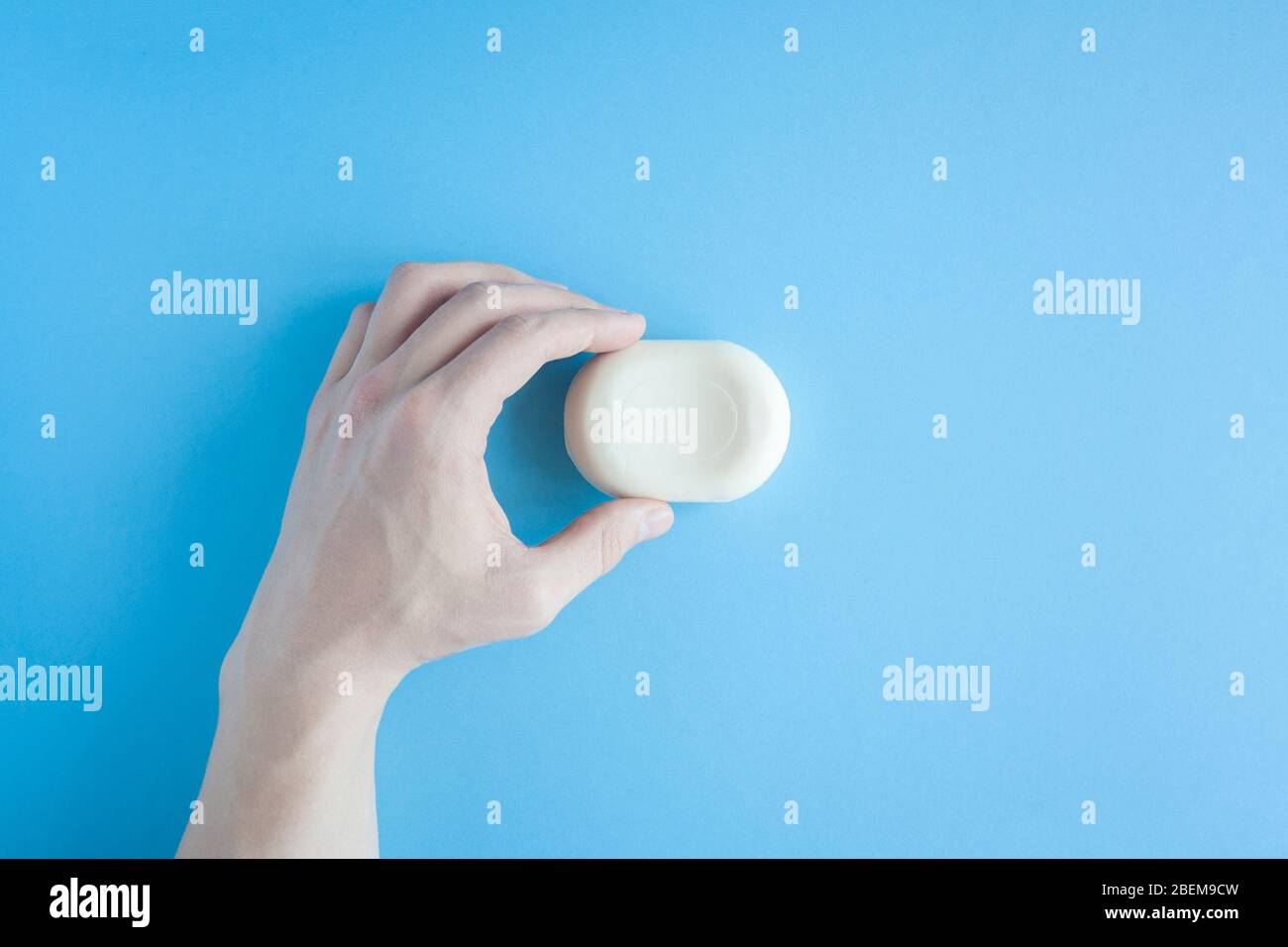 A piece of soap in a male hand a top view on a blue background. The ...