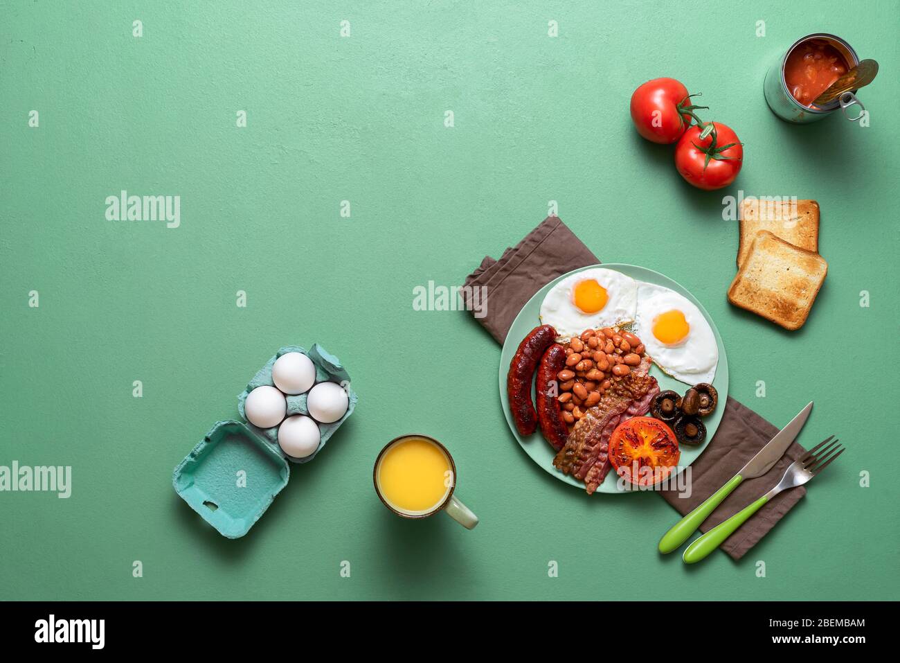 English breakfast on a plate and ingredients on a green background ...