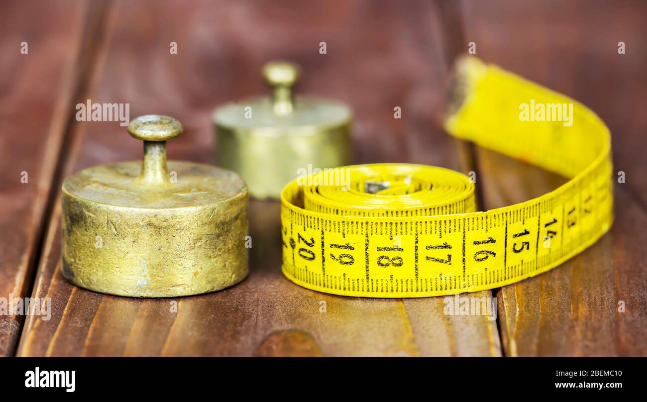 Weight loss, diet concept, tape measure and rustic metal golden weights ...