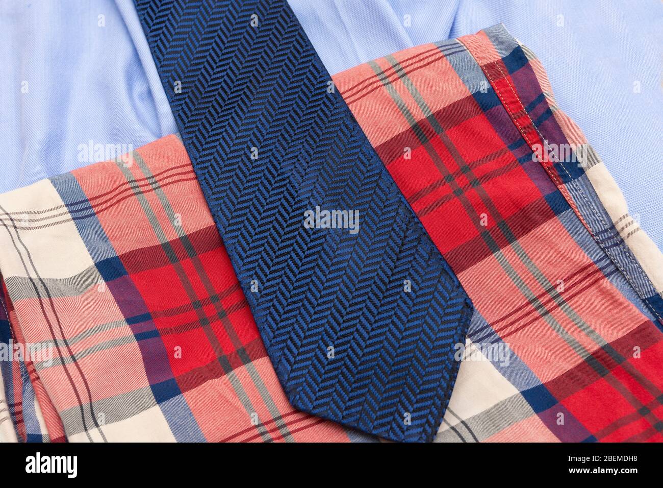 Detail of a man dressed with a blue tie, checked pajama pants and a ...