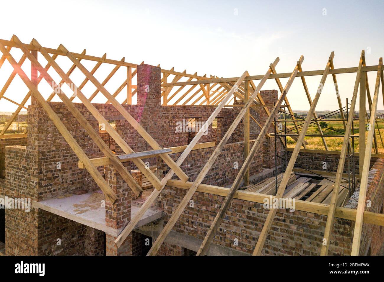 Unfinished brick house with wooden roof structure under construction ...