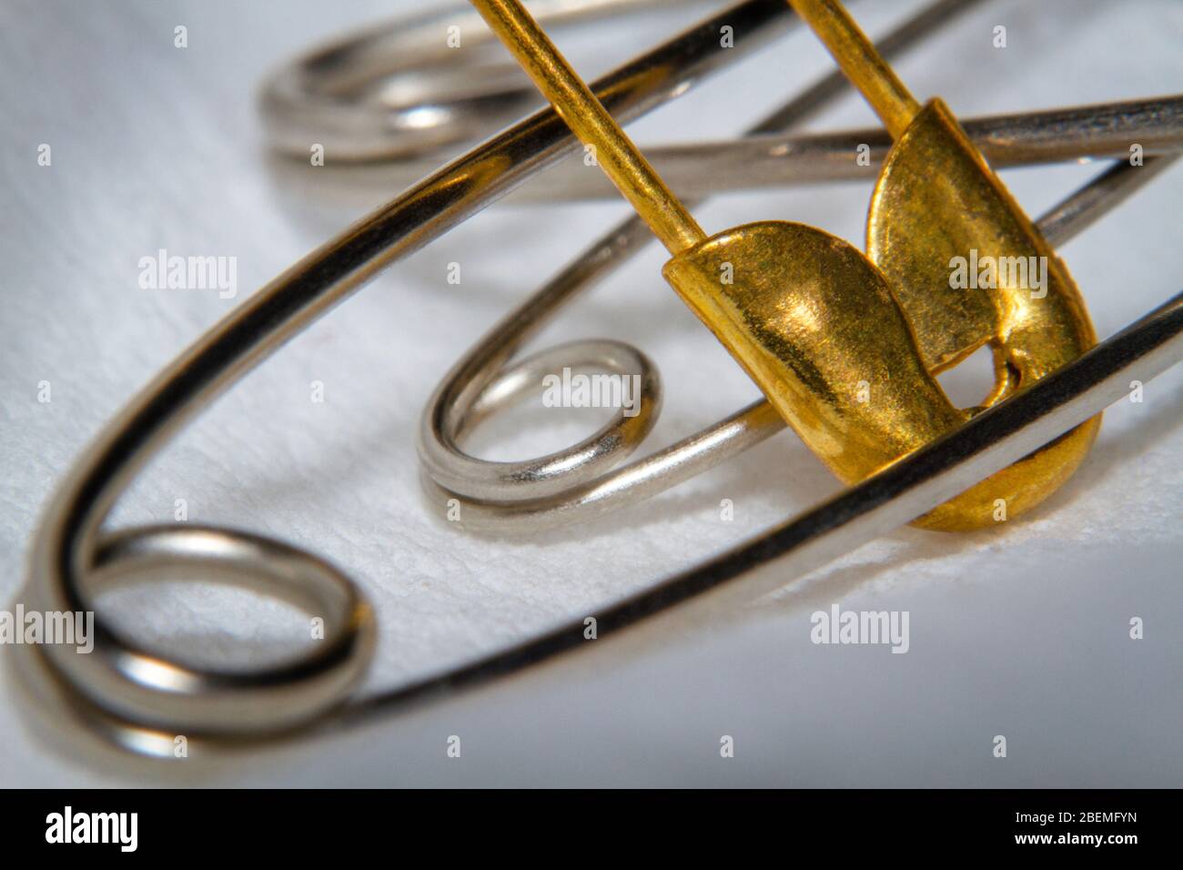 Close-up the smaller golden colour safety pin in between variation of ...