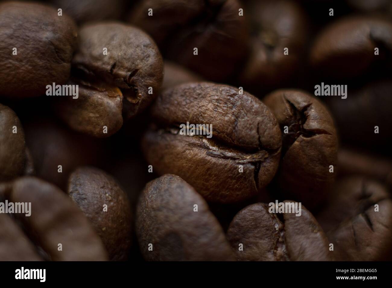 Extremely close-up background roasted coffee beans with gold streaks ...
