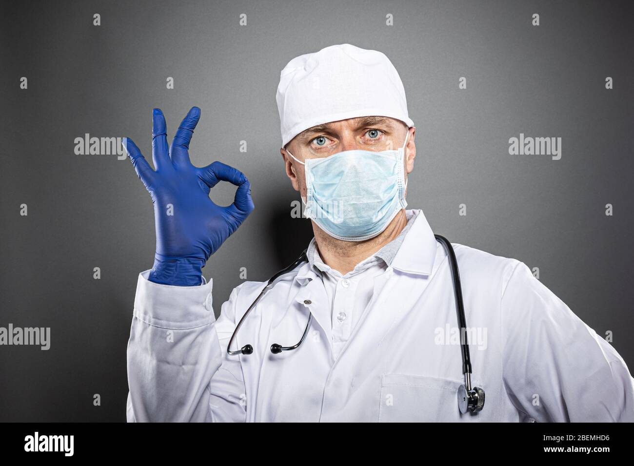 Doctor in white uniform showing OK gesture Stock Photo - Alamy