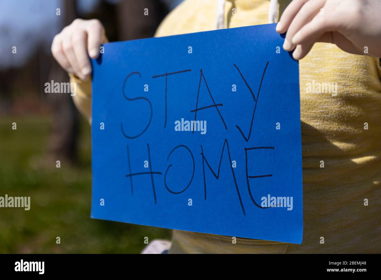 Stay Home sign on blue chroma key paper held by a man in surgical ...
