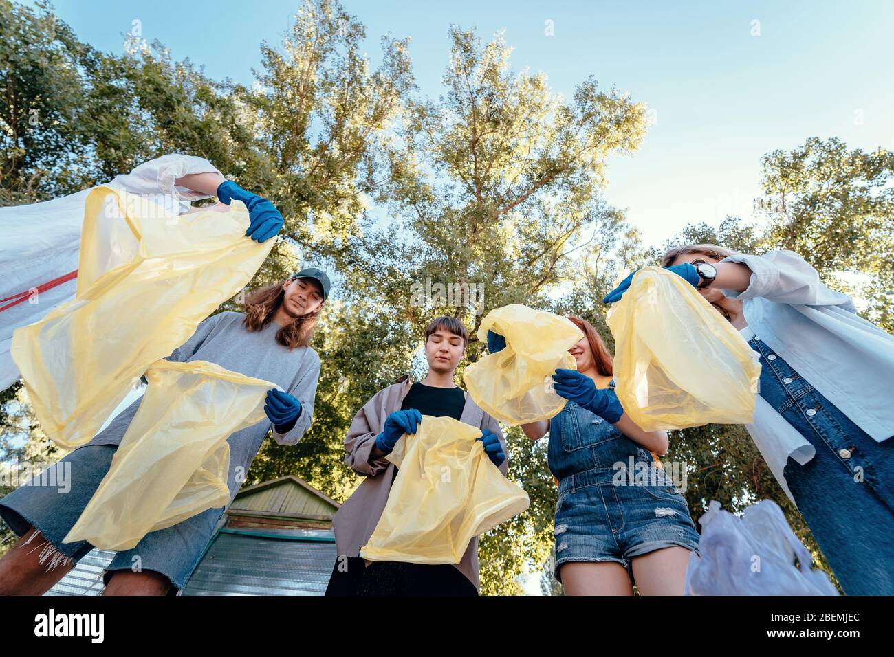 Group of activists friends throw a lot of garbage in a bag. Bottom-up ...