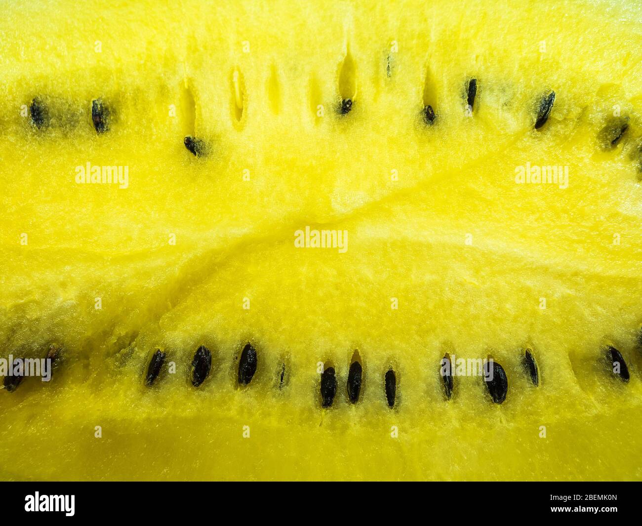 A close-up photo of the pulp of a ripe yellow watermelon with black ...