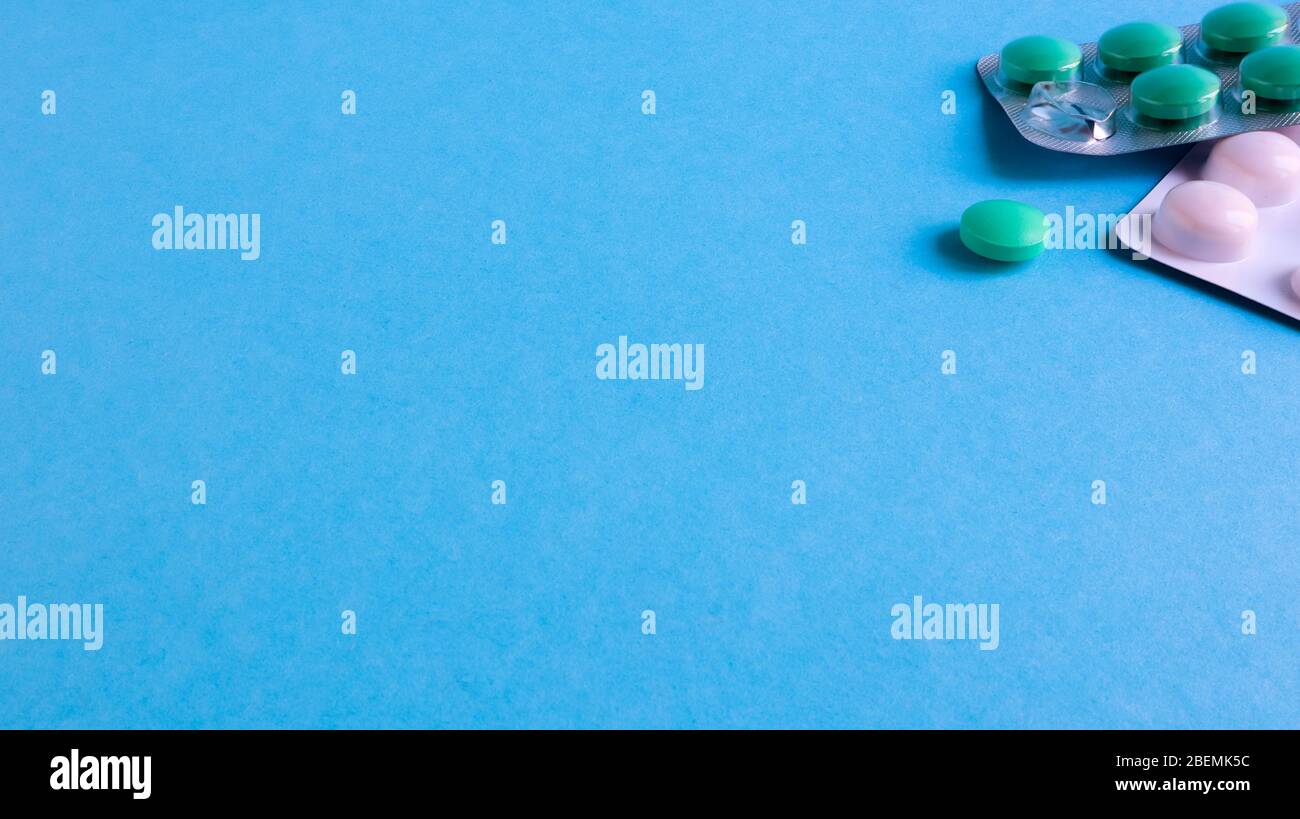 Two packs of pills and one round pill to the side on a blue background ...