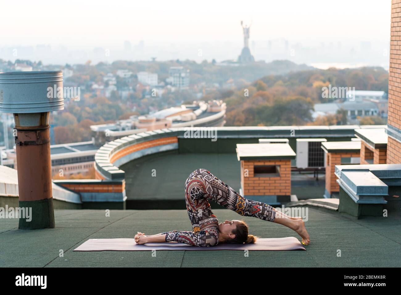 Woman doing yoga on the roof of a skyscraper in big city Stock Photo ...