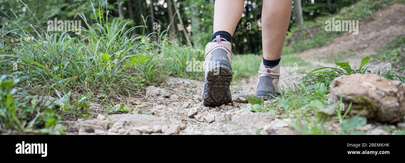 Low angle wide view image of female legs with hiking shoes on a forest ...