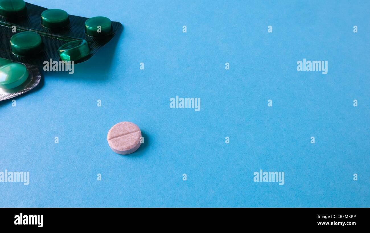 Two packs of pills and one round pill to the side on a blue background ...